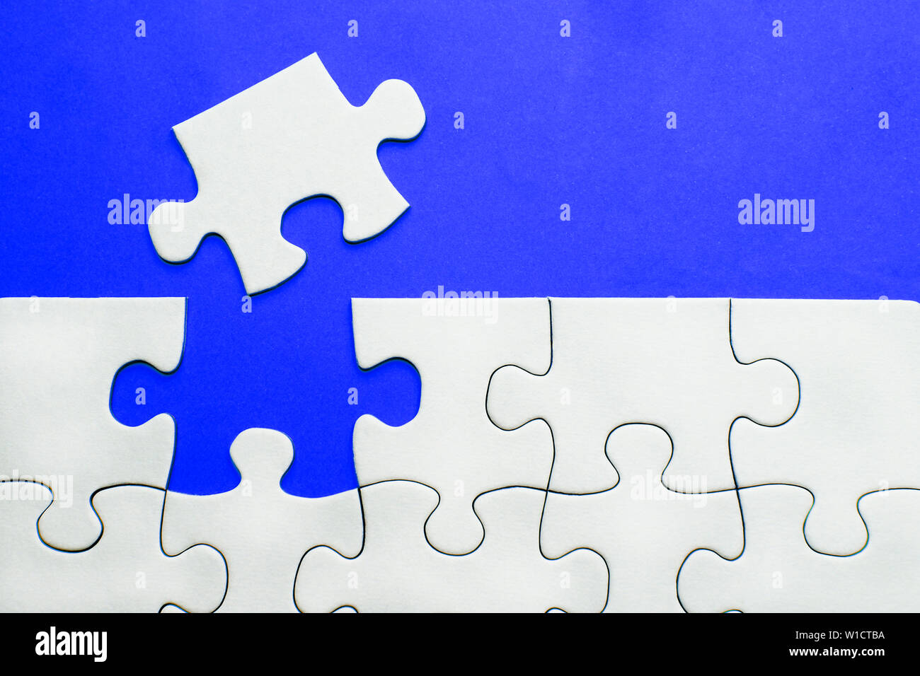 Puzzle piece missing on a blue background Stock Photo - Alamy