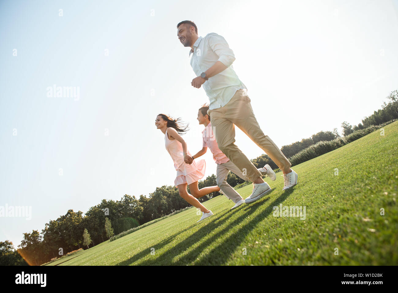 Best moments Side view of happy young family of three holding hands ...