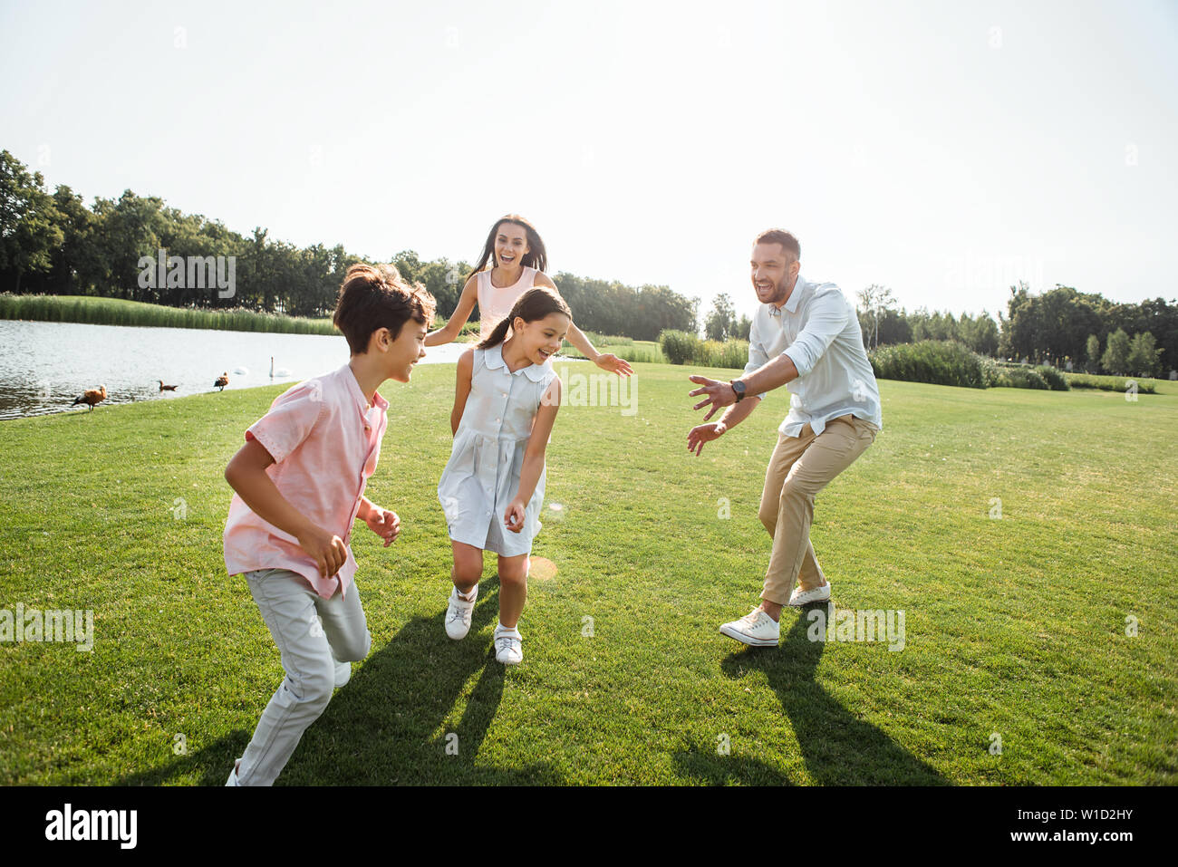 Time for fun. Happy father trying to catch his children and smiling ...