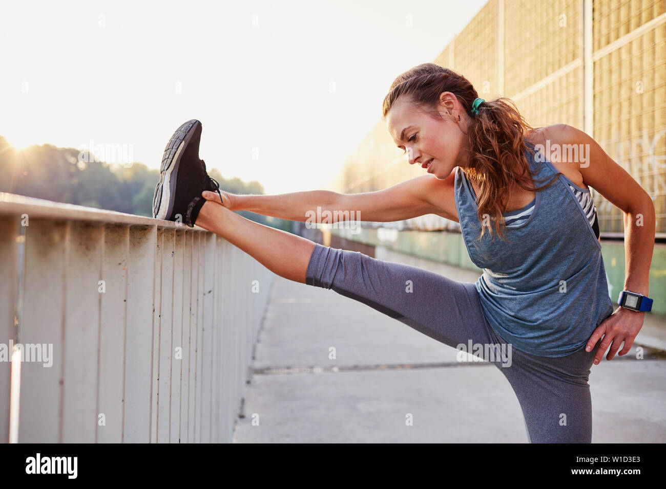 Female runner doing stretching exercise during sunny morning Stock ...