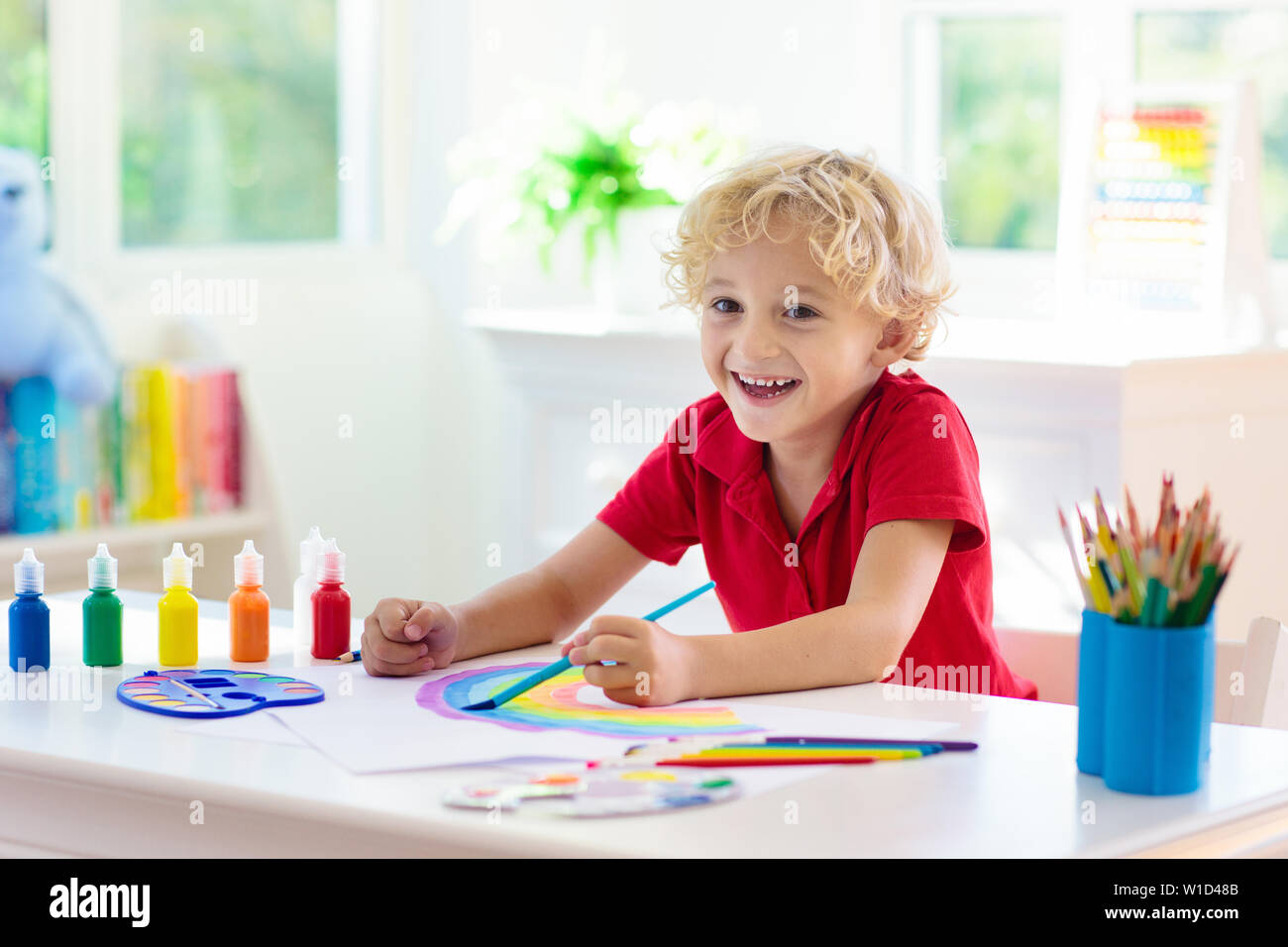 Kids paint. Child painting in white sunny study room. Little boy ...