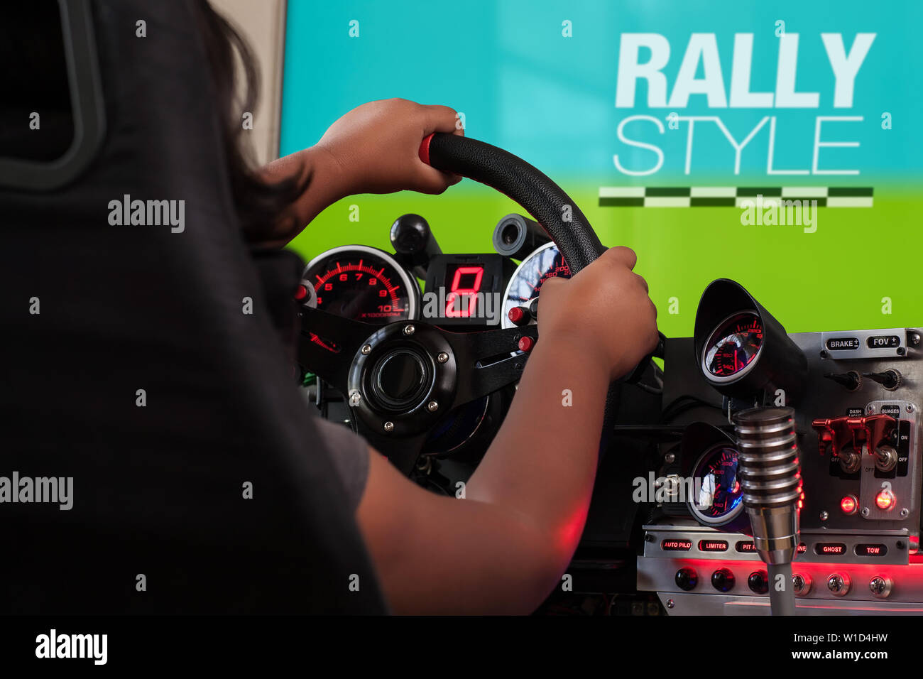 A girl playing a rally game holding a steering wheel from a racing sim ...