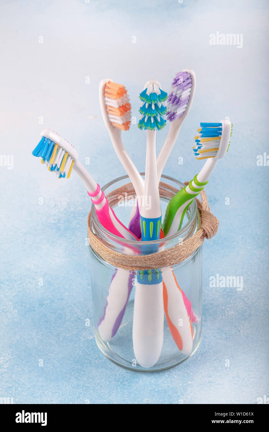 Colorful Toothbrushes in glass on blue wood background. Dental and oral ...