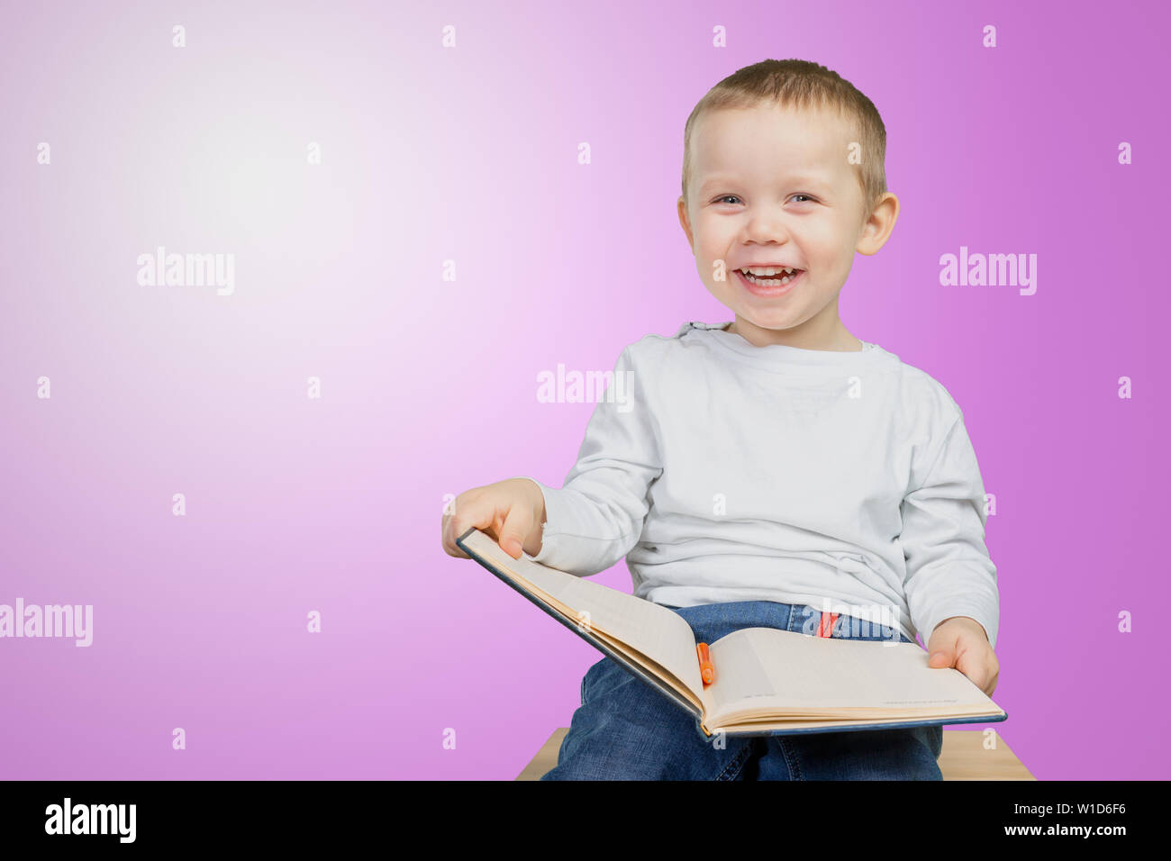 A young school boy is holding a blue book Stock Photo - Alamy