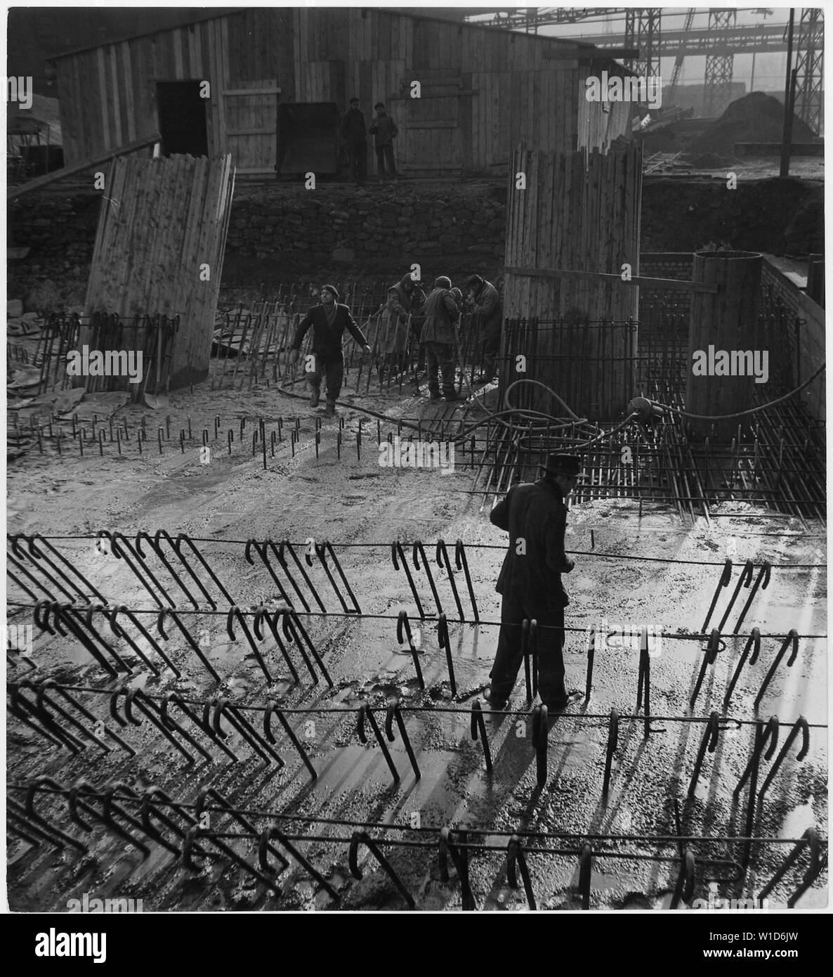 France. Standing in a bog of cement, laborer wiring on the stiffeners ...