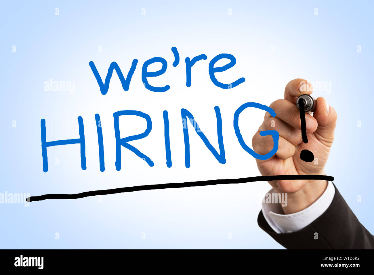 Man writing we’re hiring text using black marker on transparent display ...