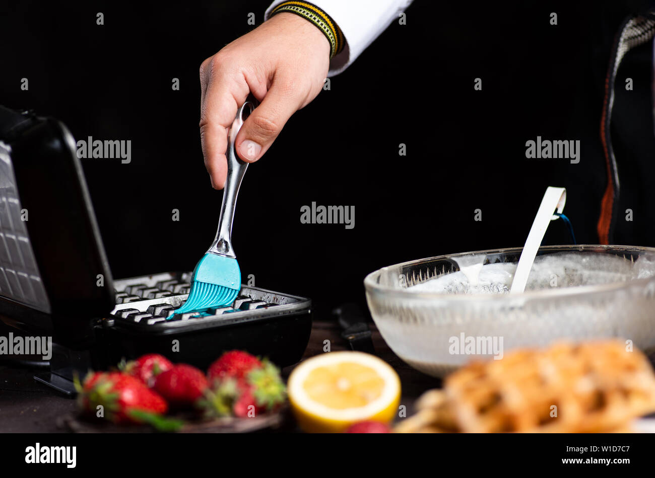 Man adding oil to waffle making machine close up Stock Photo - Alamy