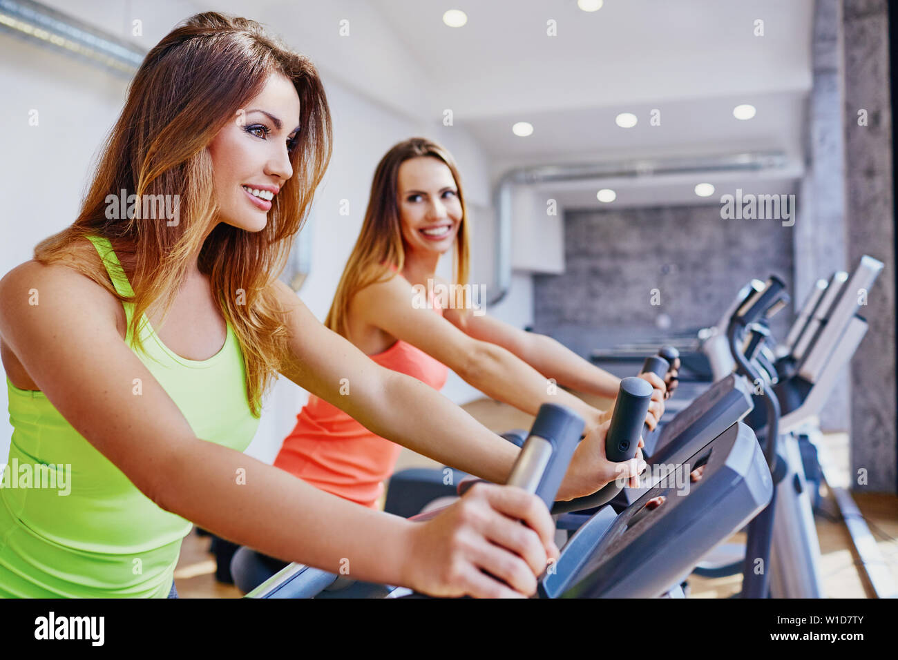 Happy women doing cardio workout on bike at gym Stock Photo - Alamy