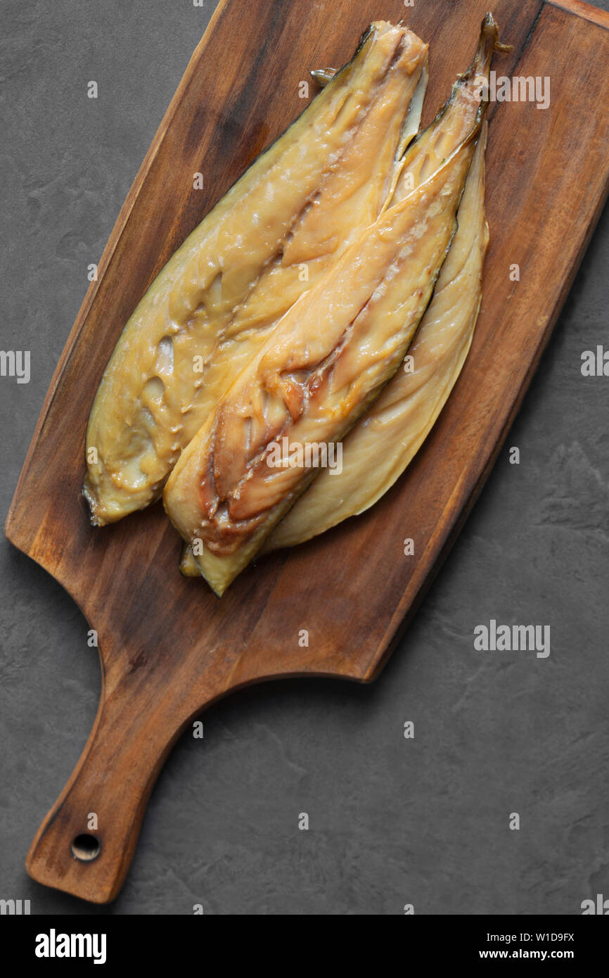 Raw smoked mackerel fillets on a rustic wooden chopping board. With a ...