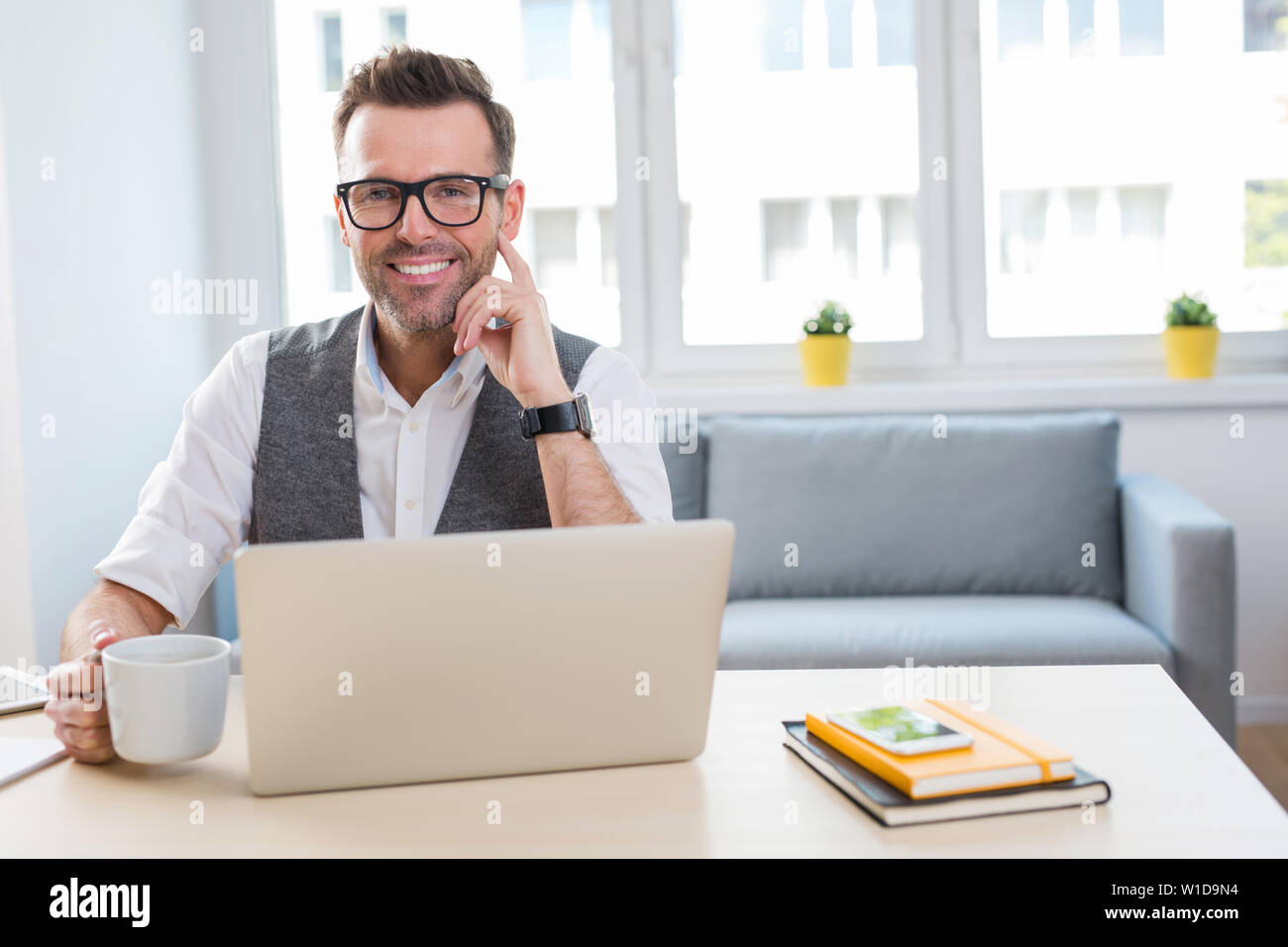 Happy man sitting at desk working with laptop from home Stock Photo - Alamy