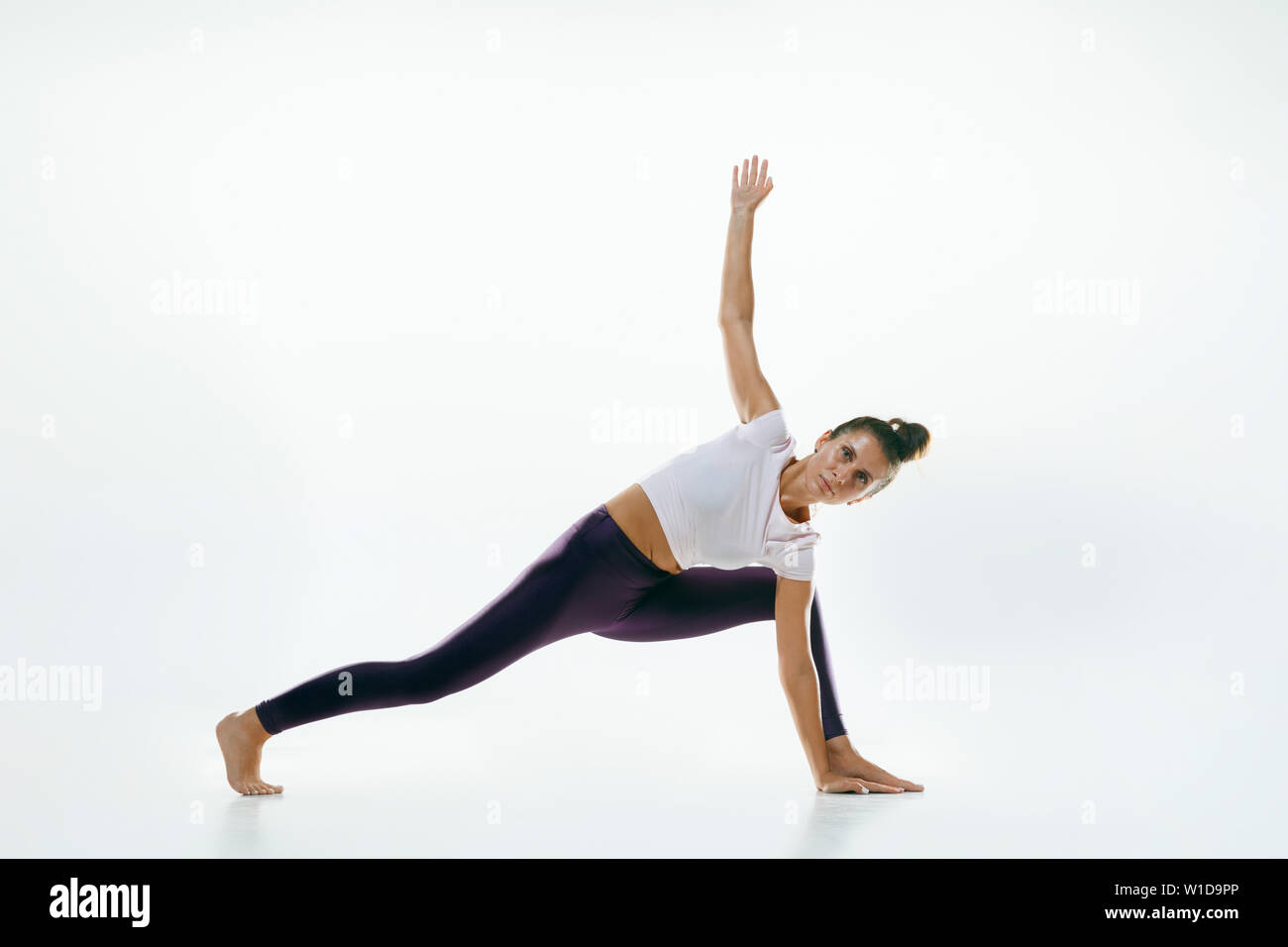 Sporty young woman doing yoga practice isolated on white studio ...
