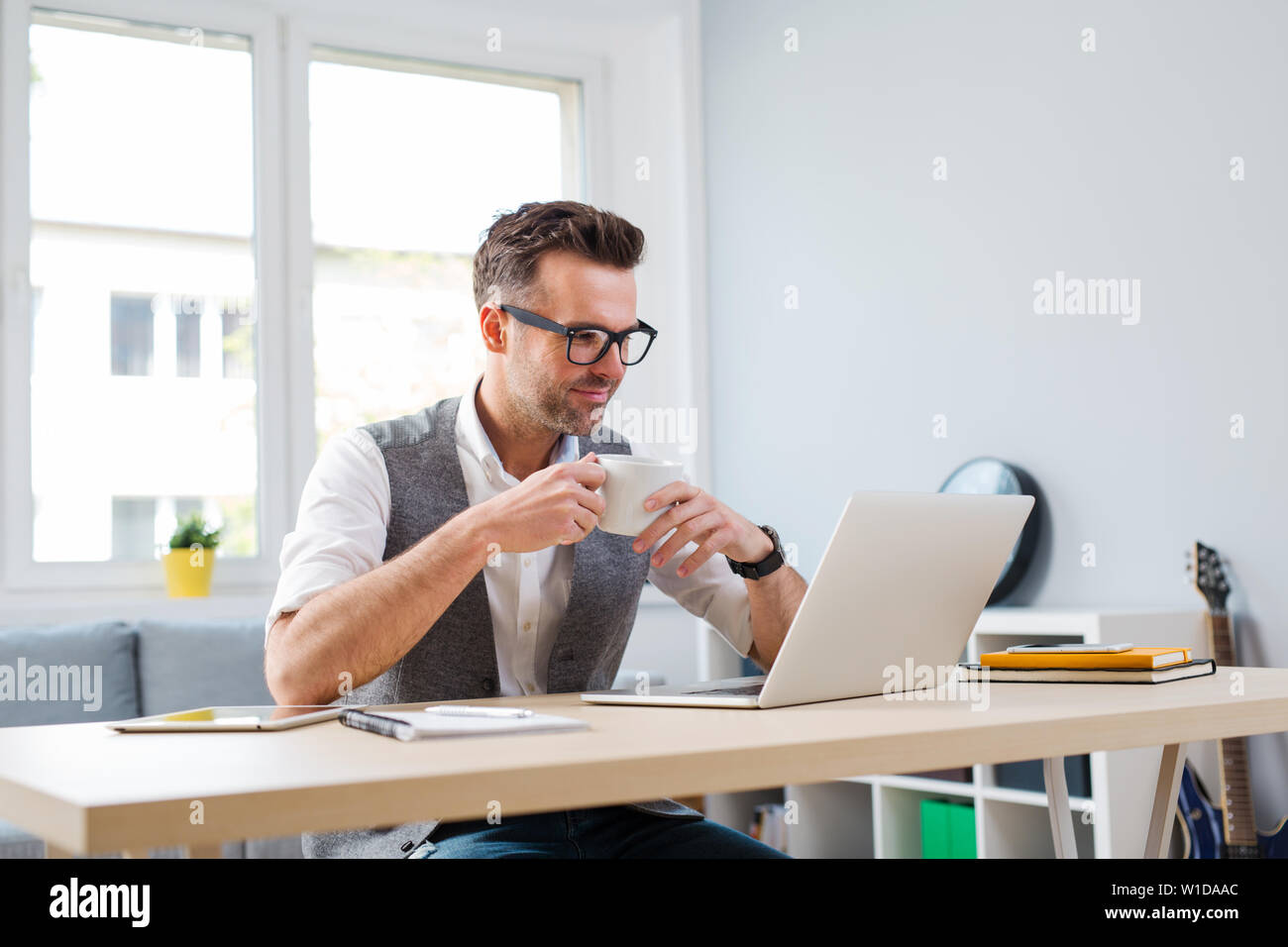 Man working from home on his laptop, drinking coffee Stock Photo - Alamy