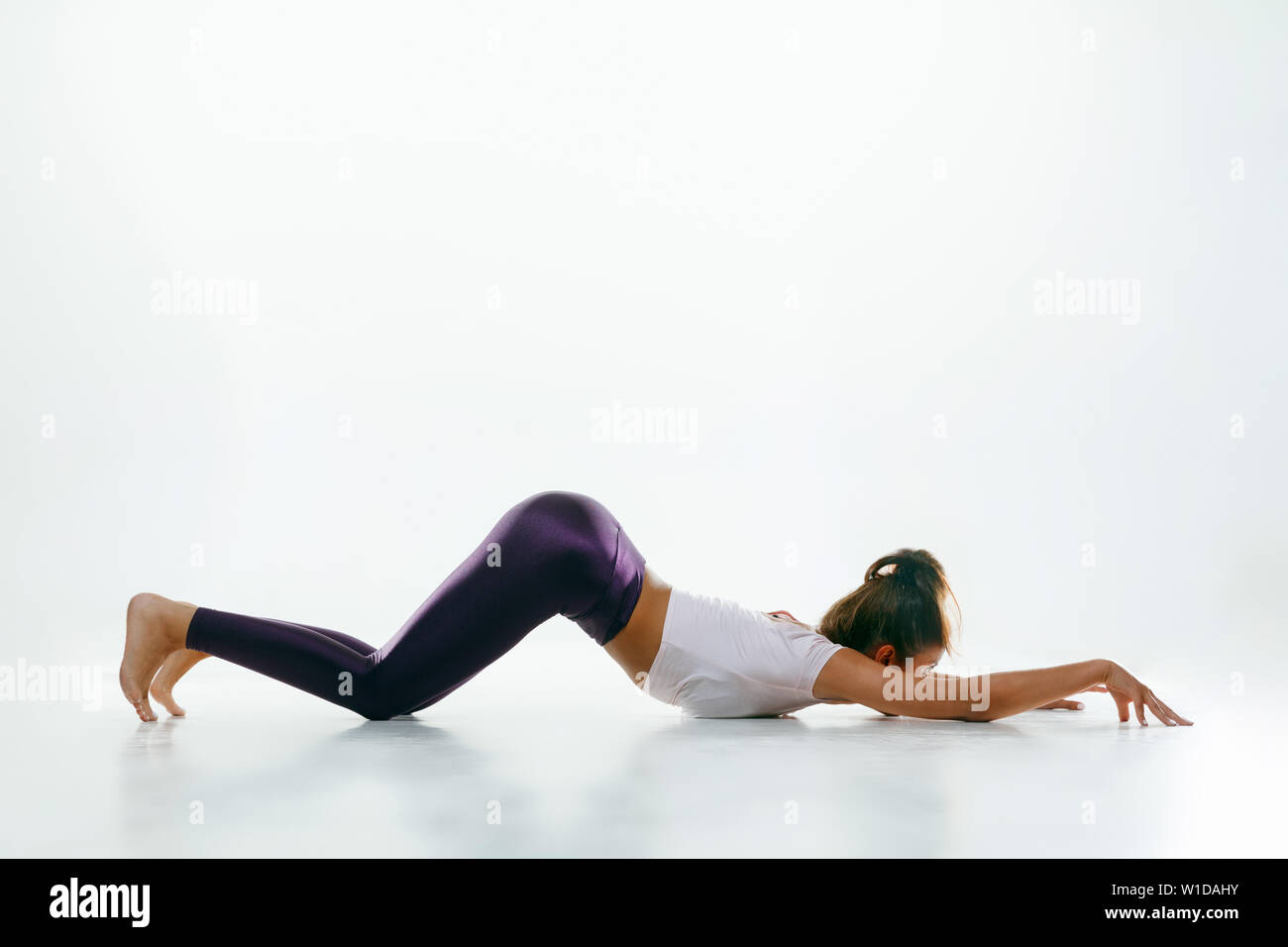 Sporty young woman doing yoga practice isolated on white studio ...