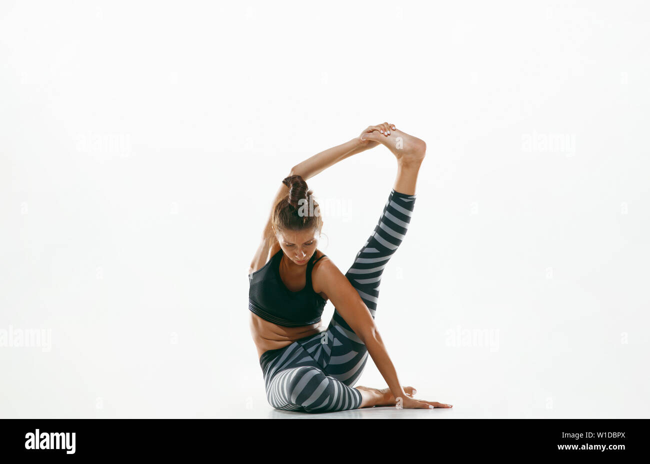 Sporty young woman doing yoga practice isolated on white studio ...