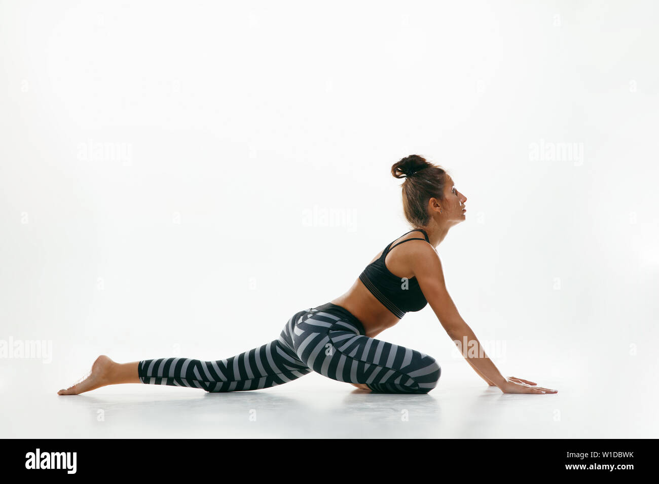 Sporty young woman doing yoga practice isolated on white studio ...