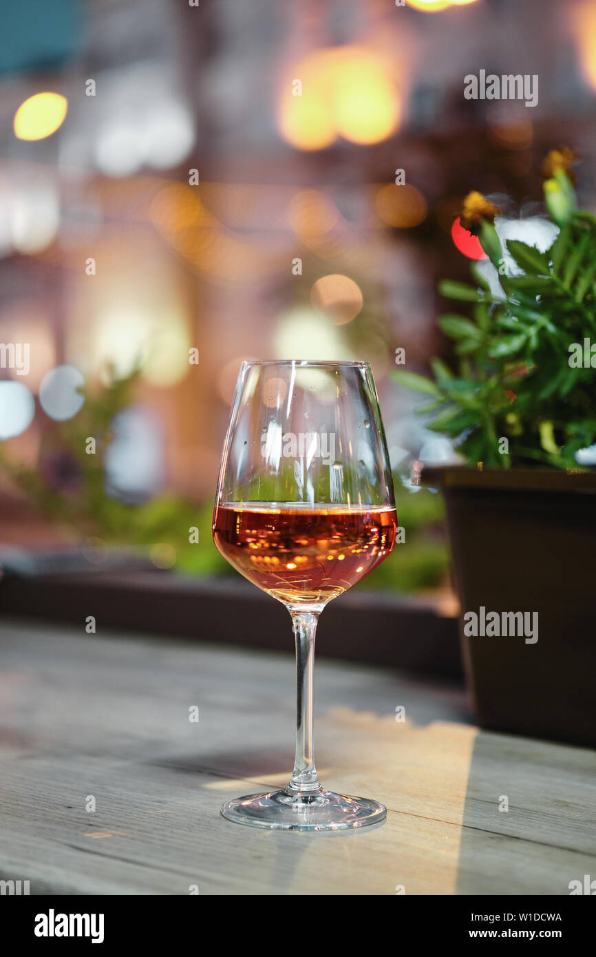 Glass of rose wine on bar counter with night city view on bacground ...
