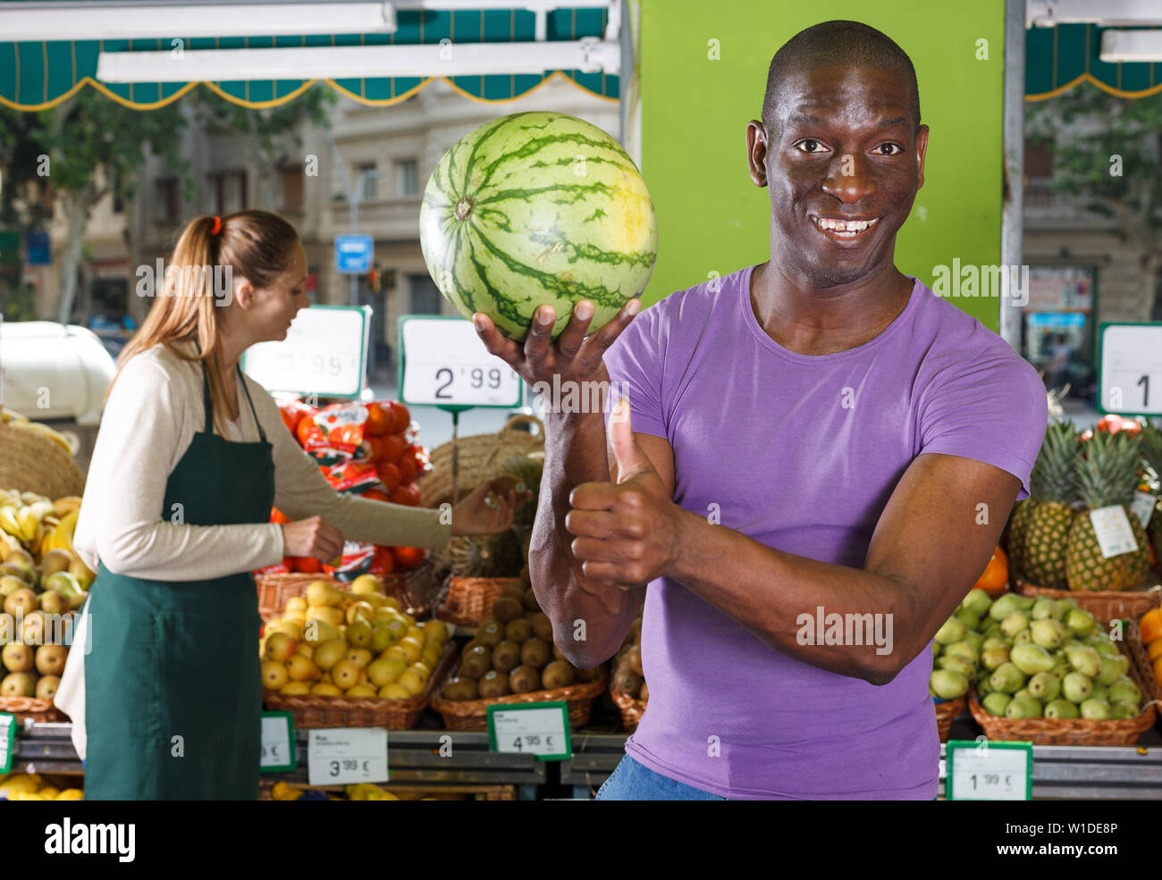 Smiling man is standing with watermelon in the fruit market Stock Photo ...