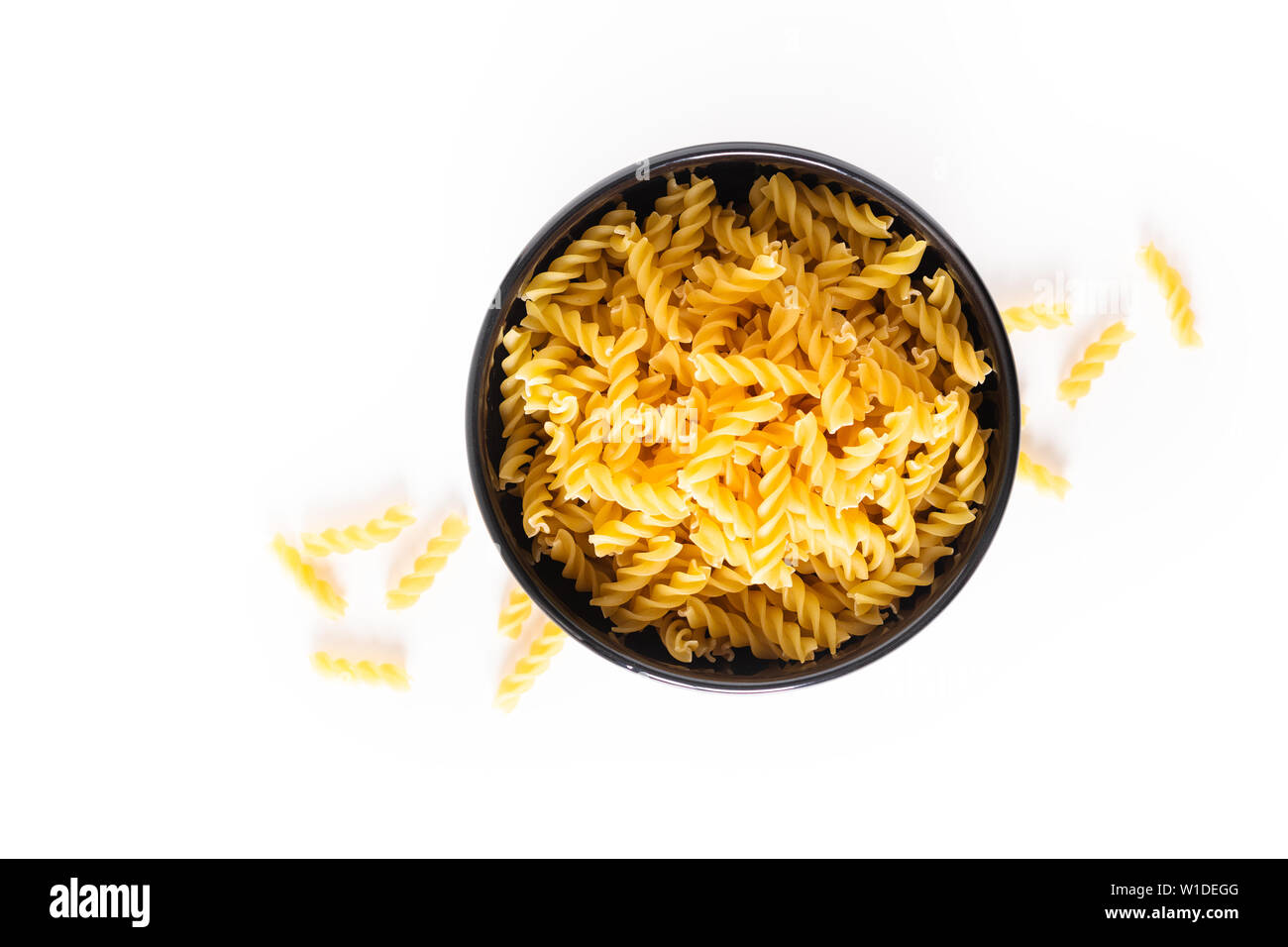 Food concept raw organic Italian Fusili pasta in black bowl isolates on ...