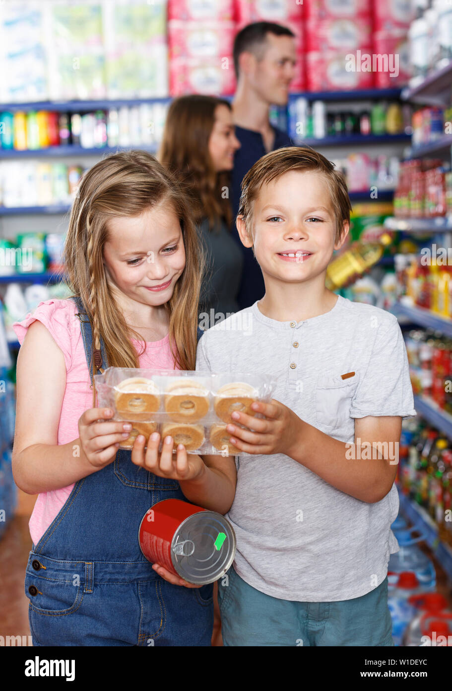 positive little children are holding meal for home in the supermarket ...