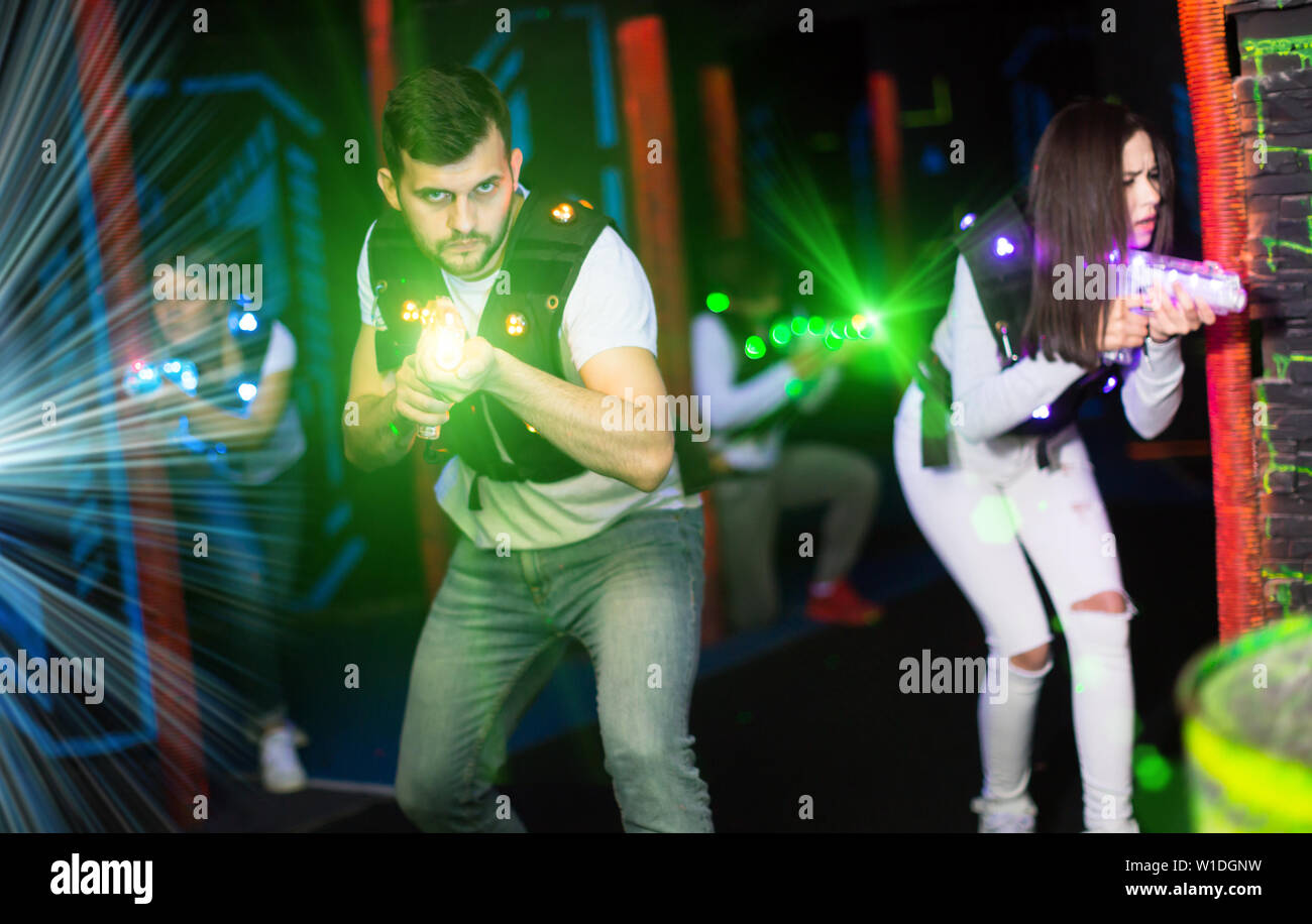 Portrait of guy in colored beams of laser guns during laser tag game on ...