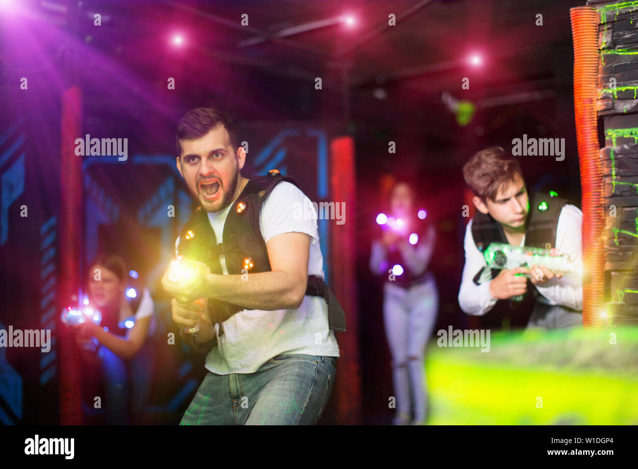 Portrait of excited guy laser tag player with laser pistol in room with ...