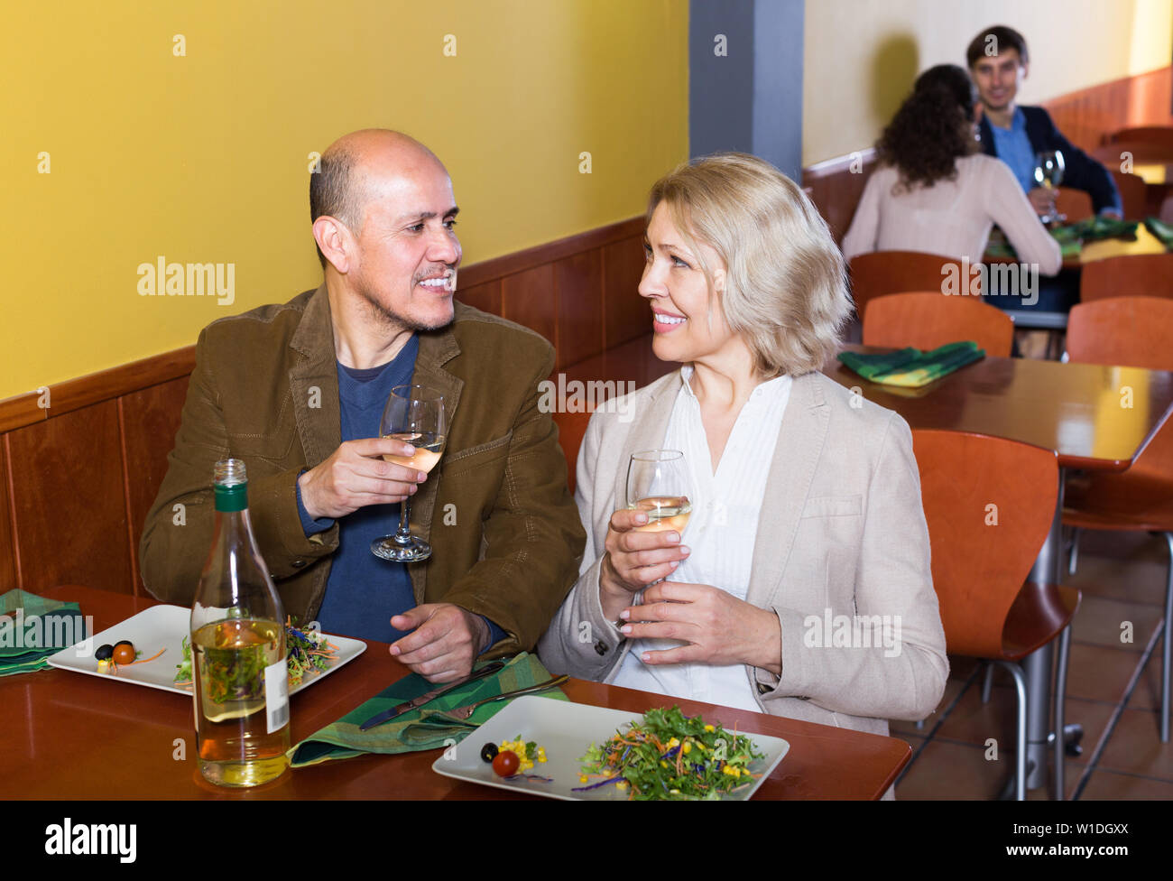 Ordinary happy elderly couple having dinner at restaurant table Stock ...