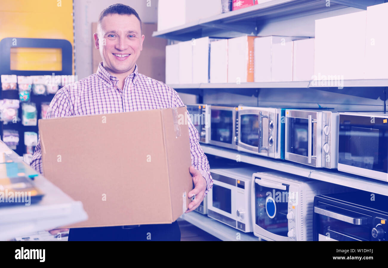 Male customer with packed purchases in household appliances section in ...