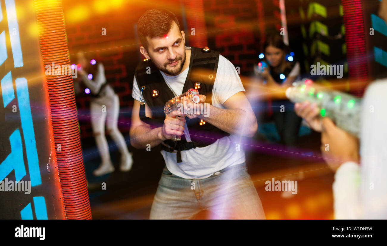 Portrait of excited guy laser tag player with laser pistol in room with ...