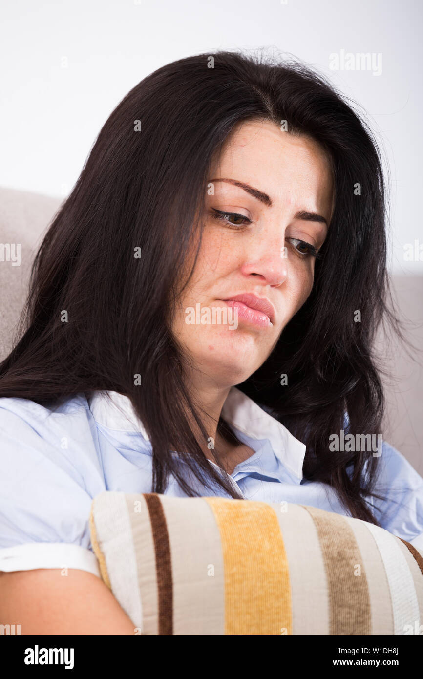 Adult sad female sitting on cozy sofa and melancholy with pillow Stock ...