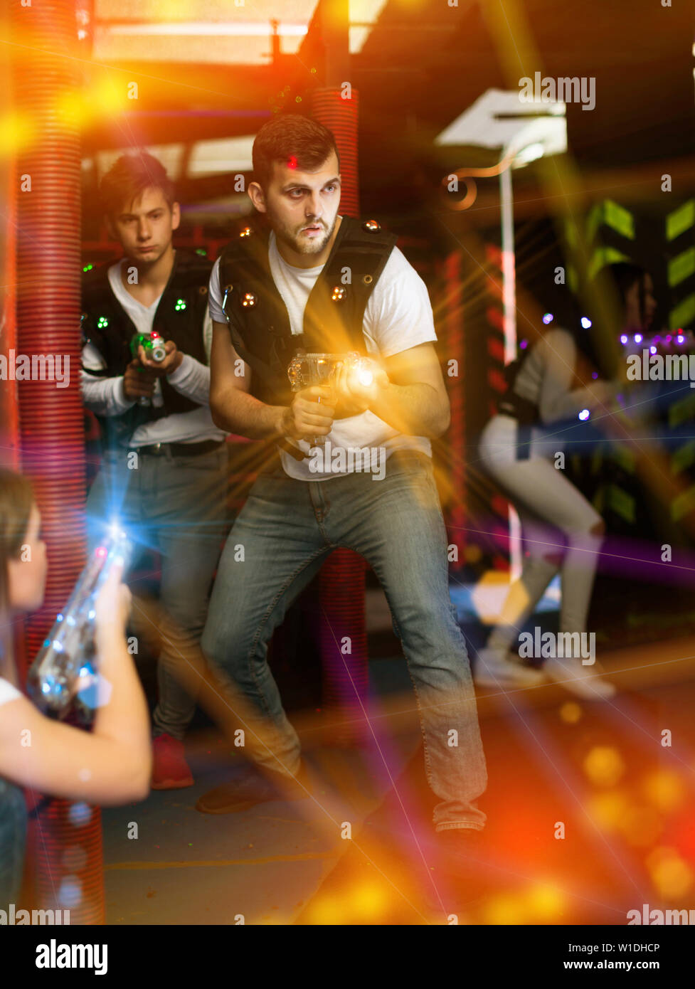 Emotional guy playing laser tag with friends on dark labyrinth in ...