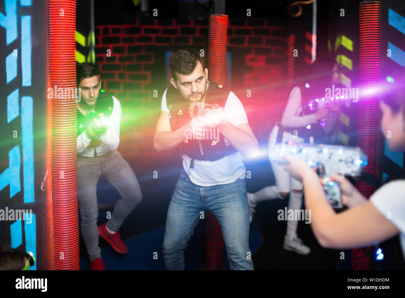 Emotional guy playing laser tag with friends on dark labyrinth in ...
