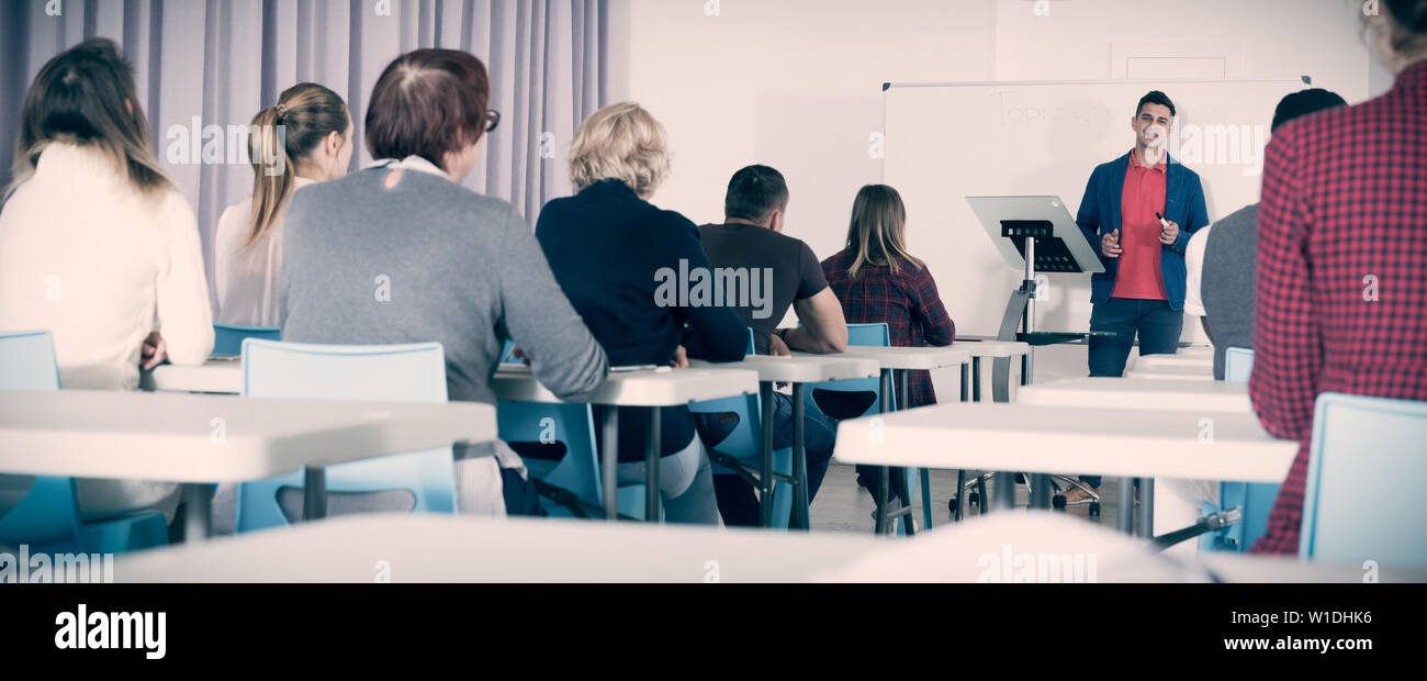 Students of different age sitting together at tables, doing group study ...