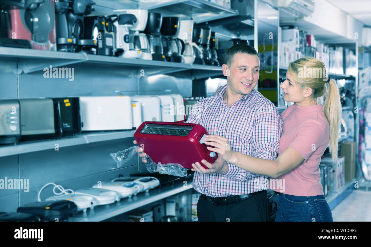 Positive family choosing new kitchen toaster in household appliances ...