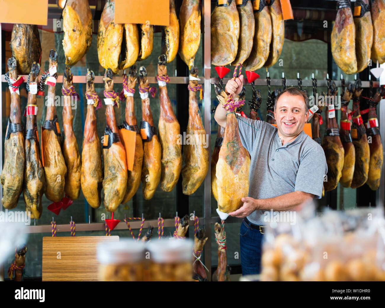 Happy glad smiling mature customer buying iberico or serrano jamon leg ...