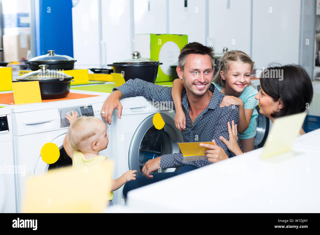 Glad family with two kids together choosing washing machine in shop of ...