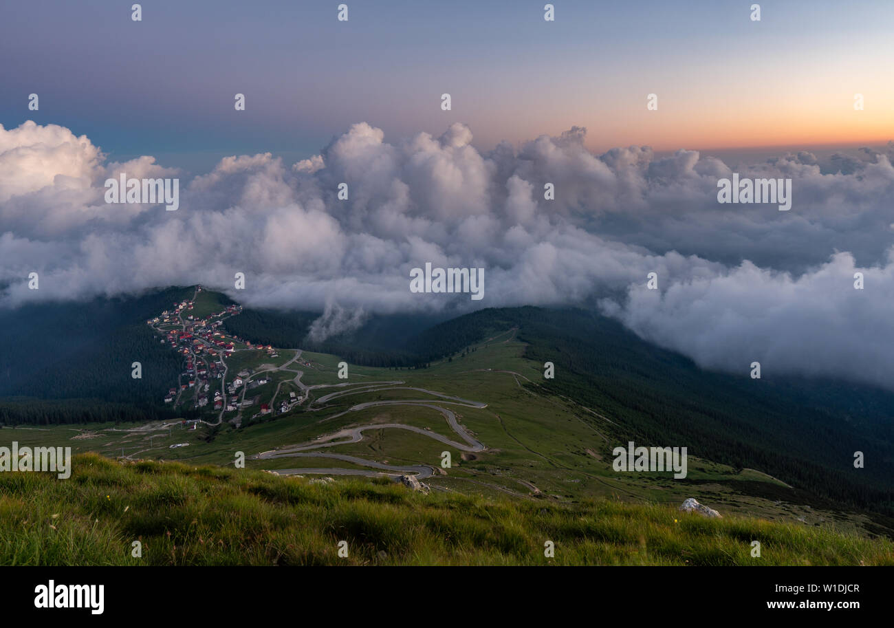Mountain resort with hotels and houses at sunset with clouds above ...