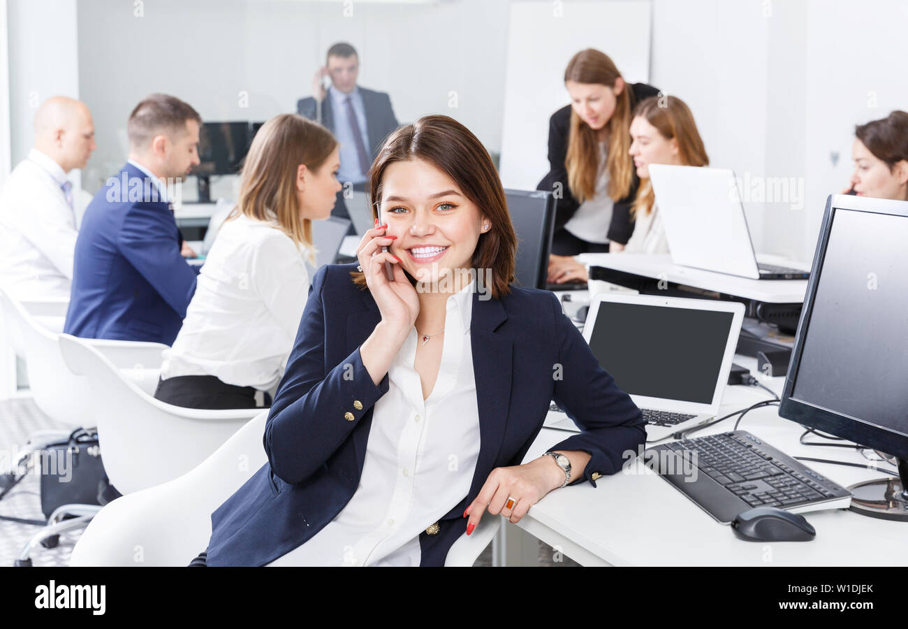 Young smiling businesswoman having phone call conversation at workplace ...