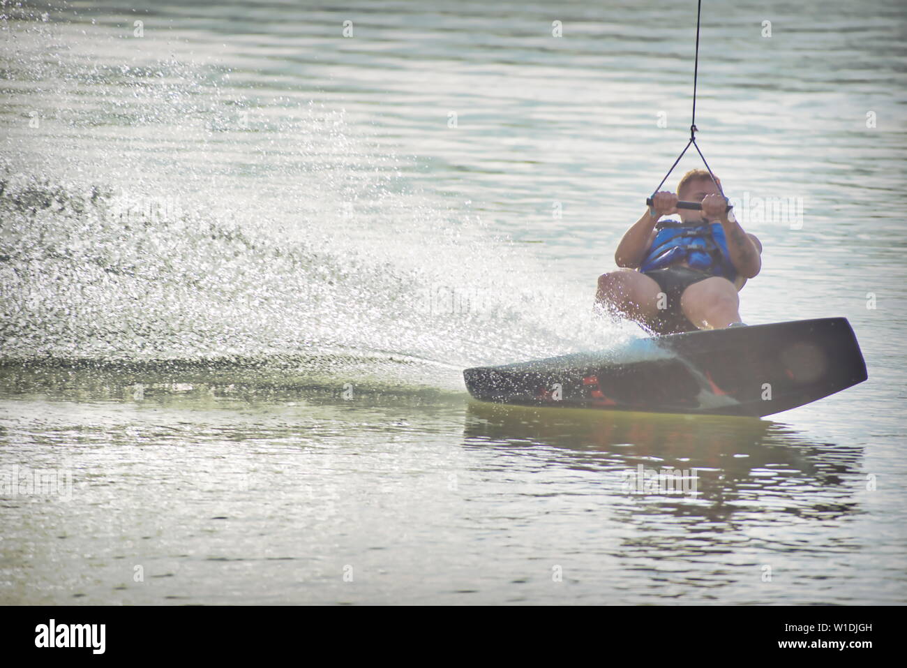 Wakeboarder making tricks. Low angle shot of man wakeboarding on a lake ...