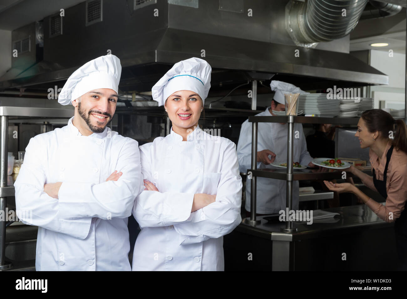 Portrait of two confident chefs posing with crossed arms in ...
