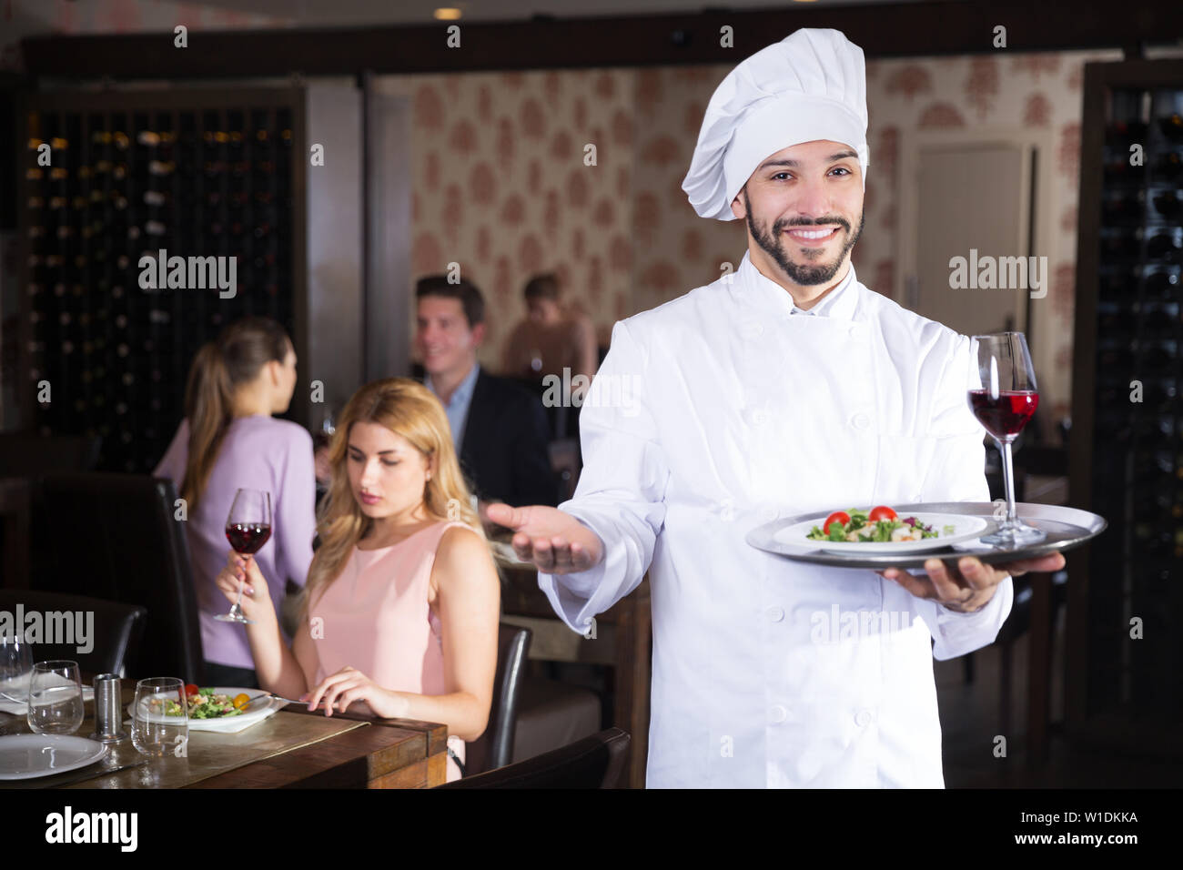 male chef with dishes on serving tray welcoming to restaurant Stock ...