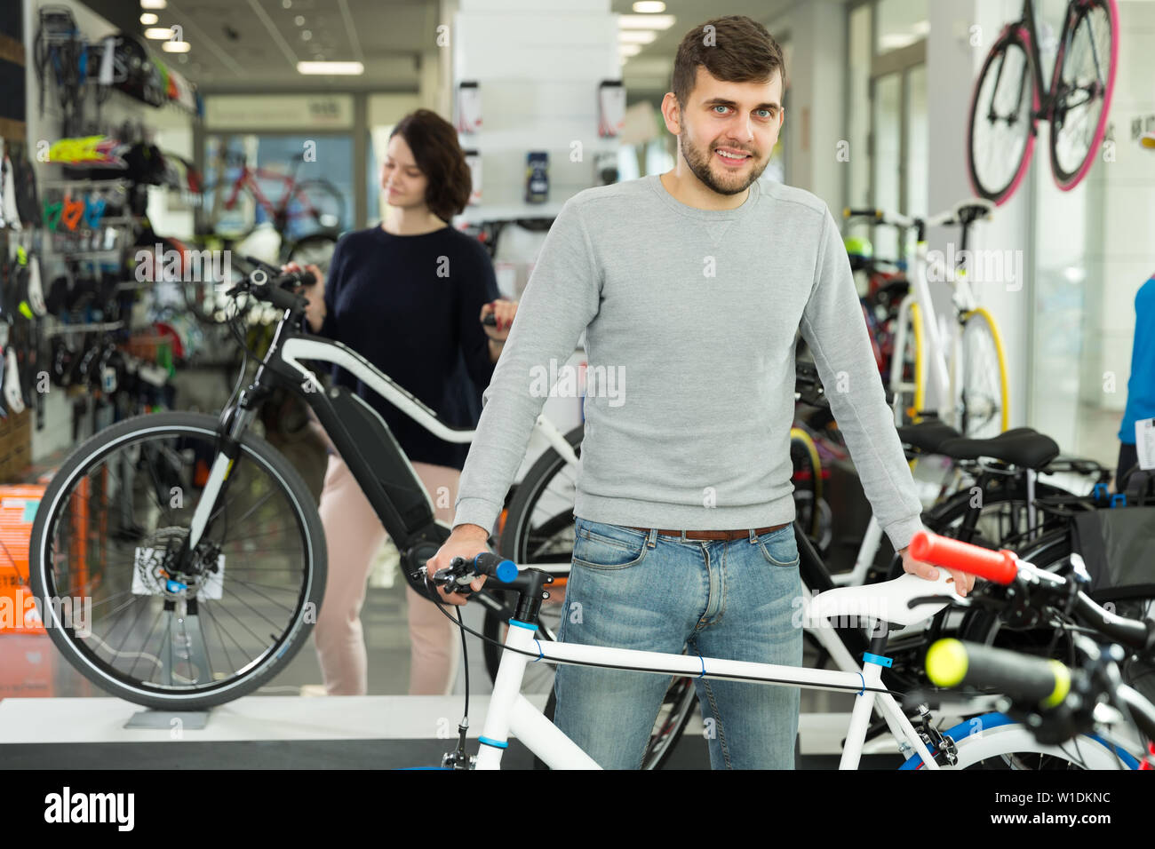 Young man standing with sport bike in bicycle store Stock Photo - Alamy