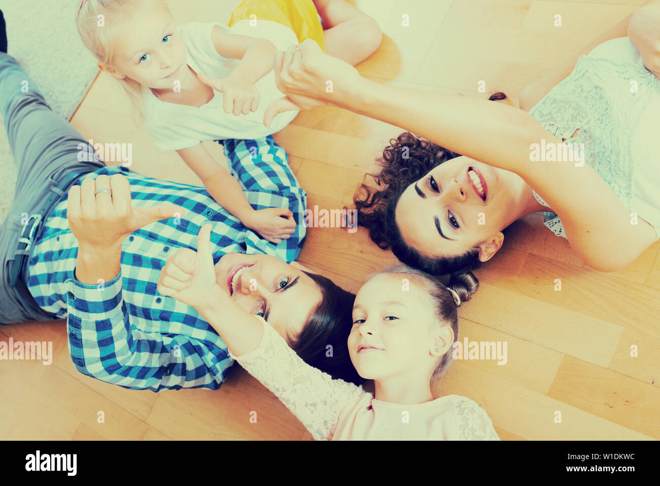 Family values: portrait of positive parents with little girls indoors ...