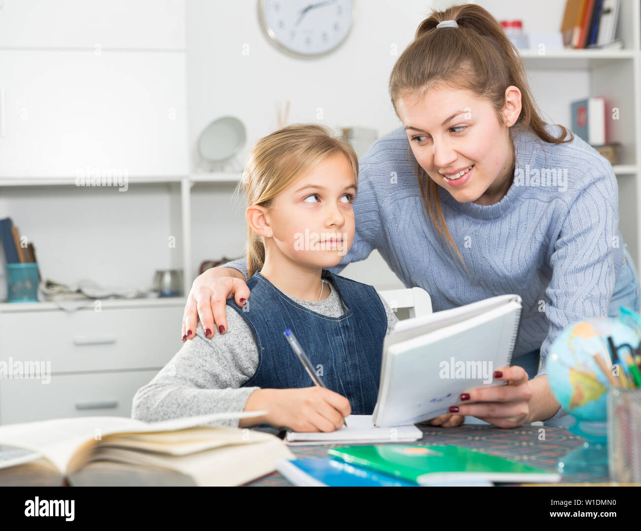 Mother checks school lessons daughters Stock Photo - Alamy