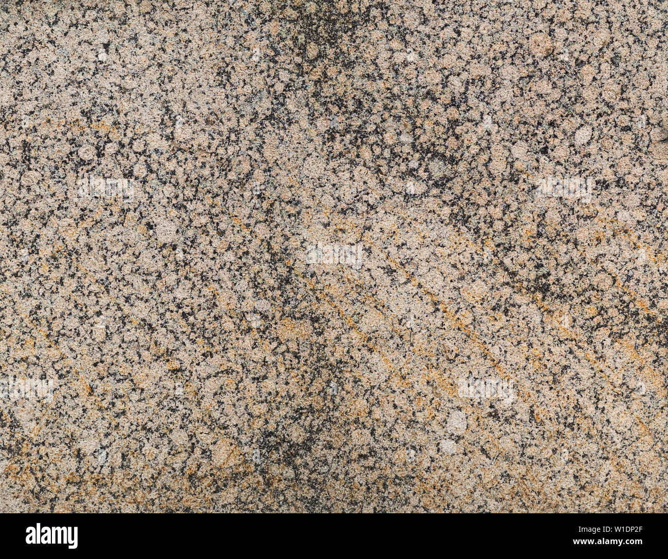 Close-up of a spotted light red or orange and black granite stone wall ...