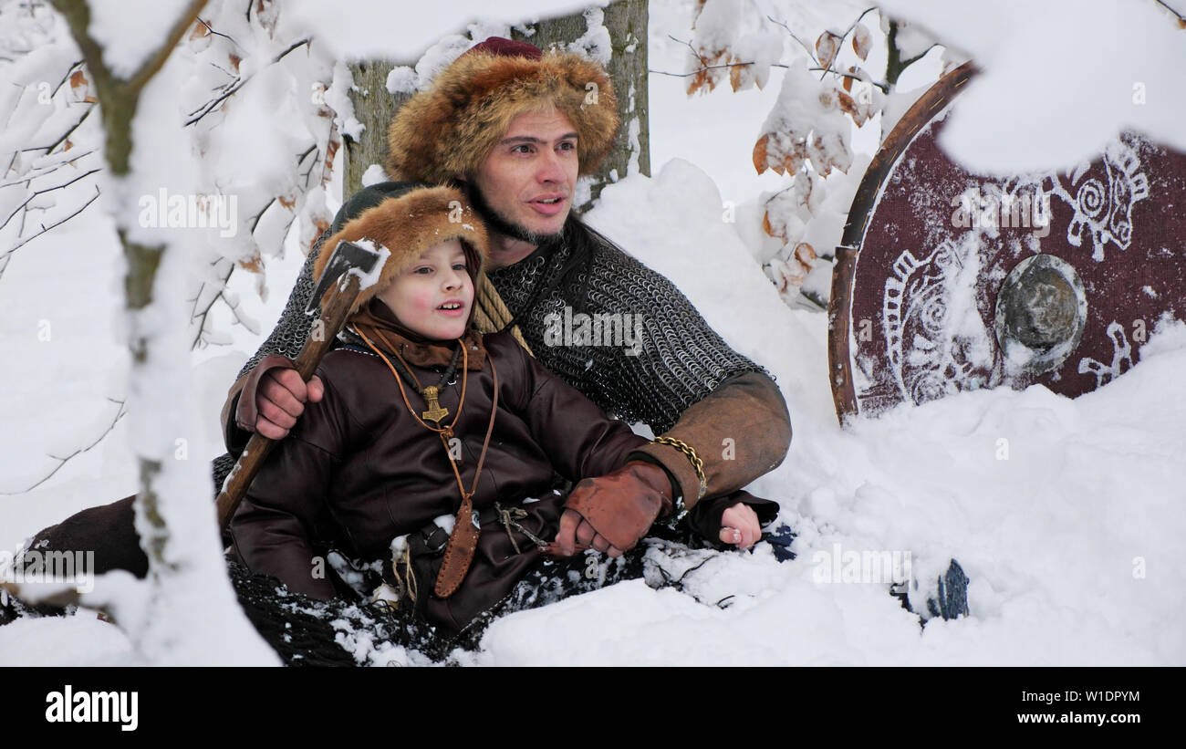 Father viking and his son sits and talking on the snow in the winter ...