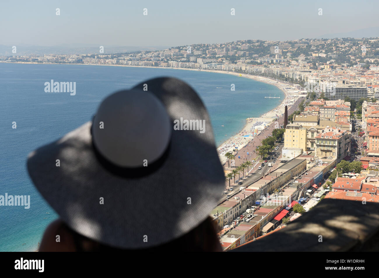 Nice, France - June 19, 2019: Woman in a hat looks at the beach and ...