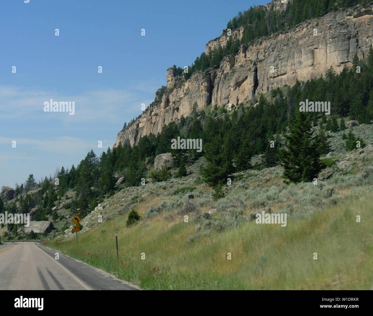 Cropped side view shot of tall steep granite cliffs from the road, with ...