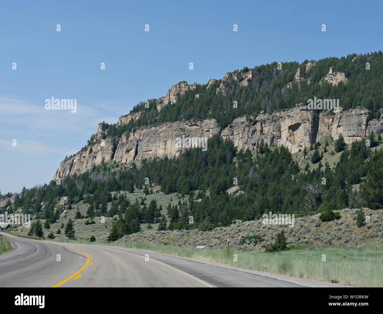Side view of tall steep granite cliffs from the road, with a roadside ...