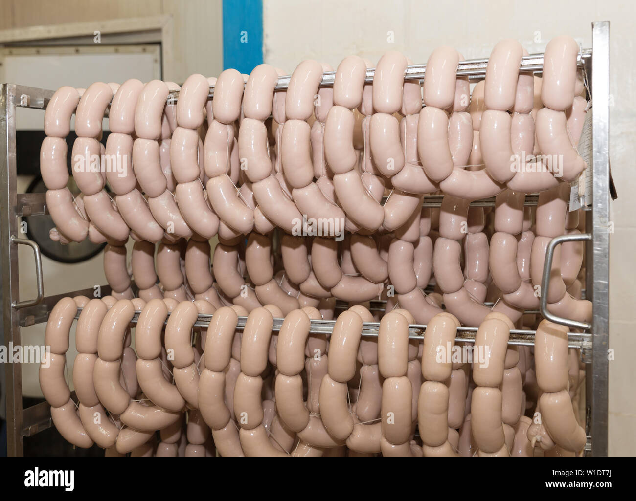 Raw sausages on racks in storage room at meat processing factory Stock ...
