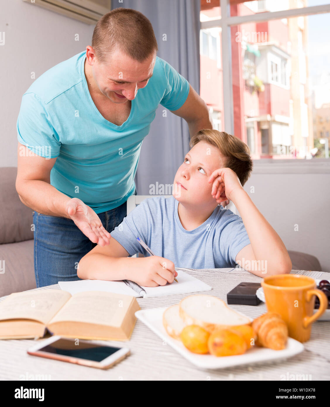 Adult male is helping his son are writing homework at the home Stock ...